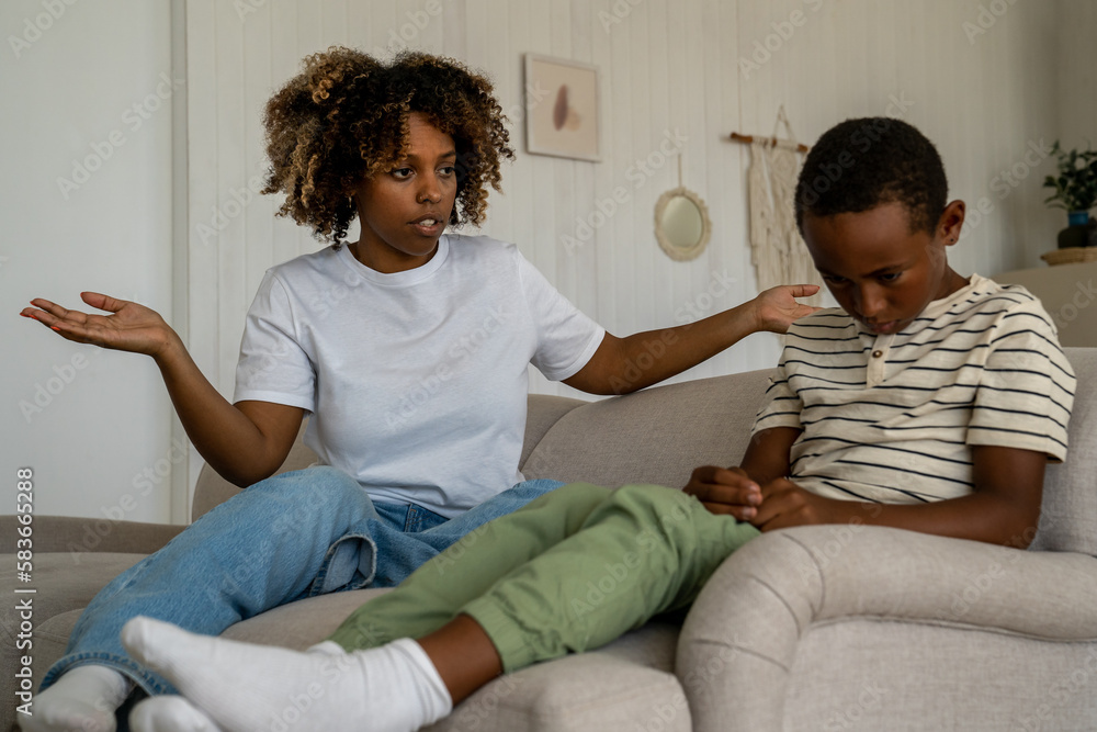 Foto Stock Dissatisfied African American woman mother scolding upset son for bad behavior while ...