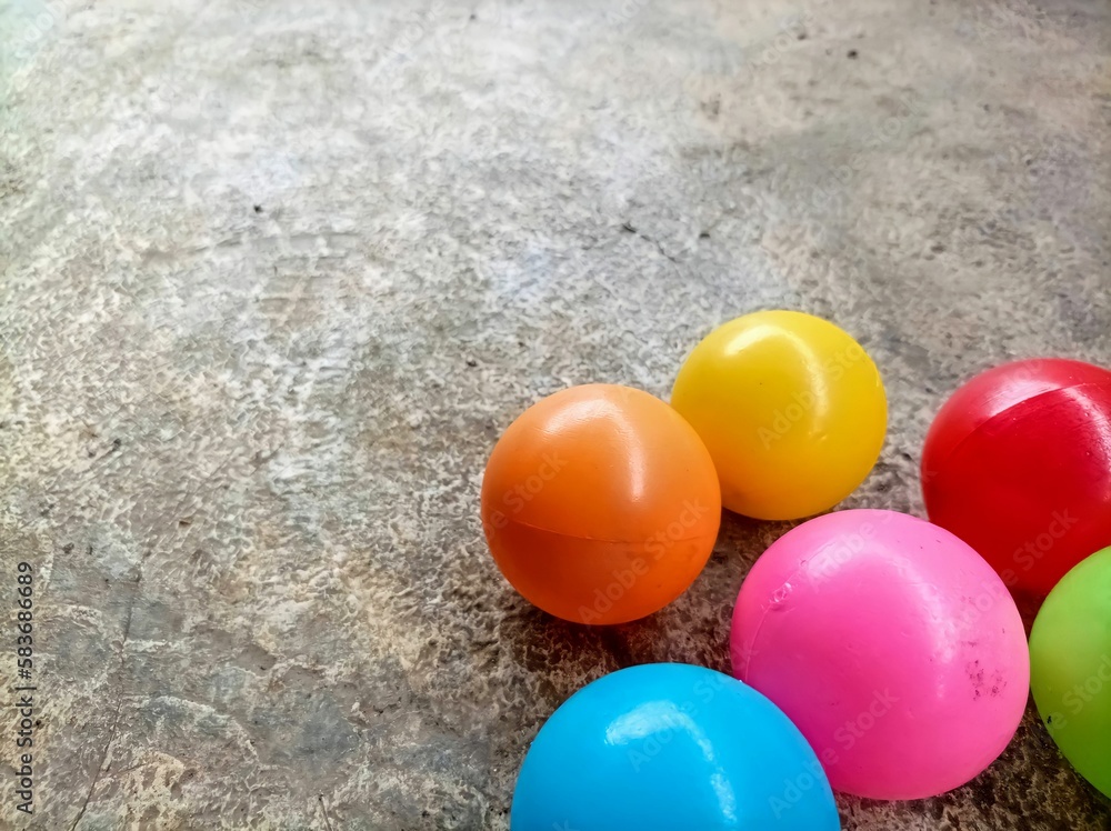 Top view of multicolor plastic balls on cement texture as the ...