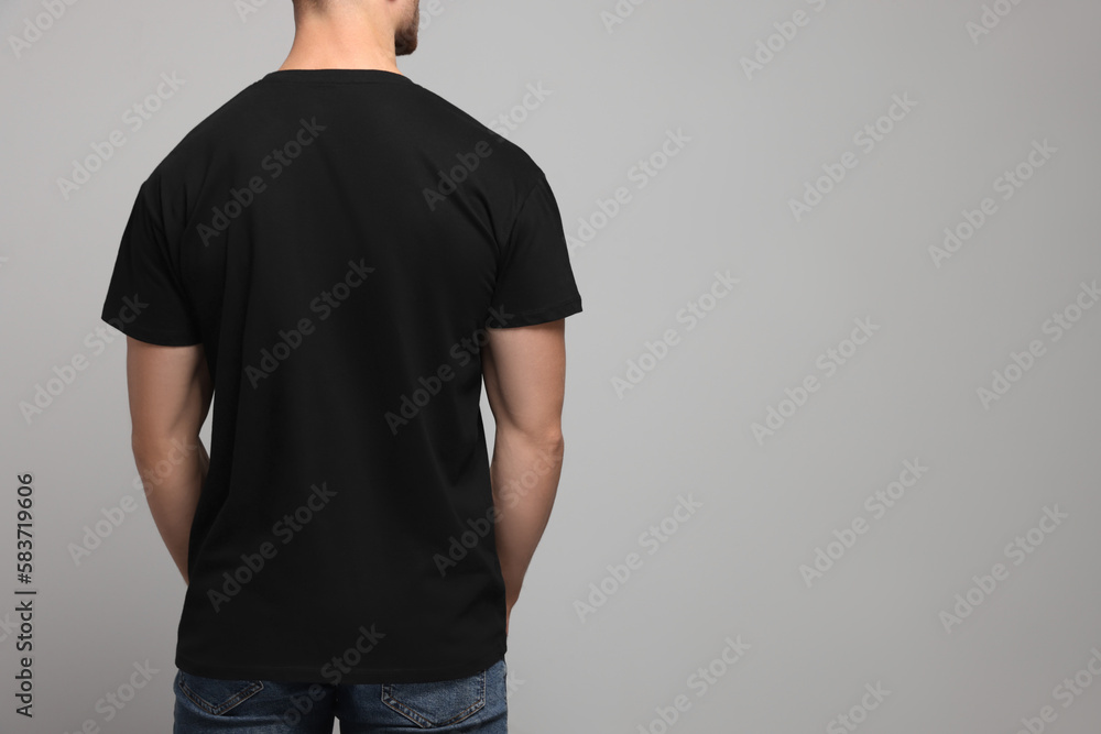 Man wearing black t-shirt on light grey background, back view. Mockup ...