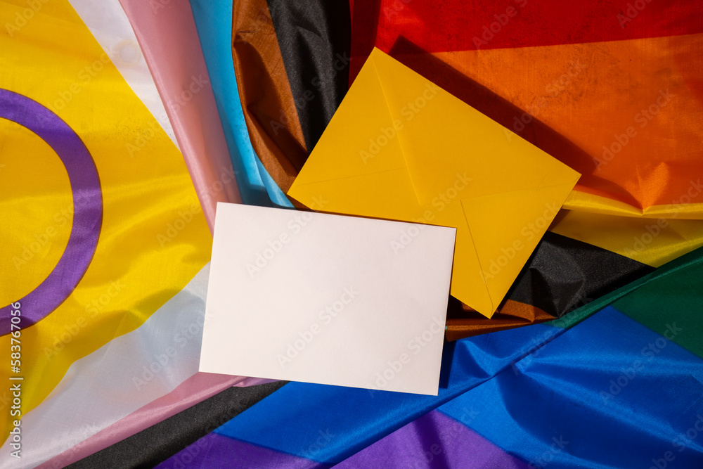 Empty paper blank on Rainbow LGBTQIA flag made from silk material. Mock ...