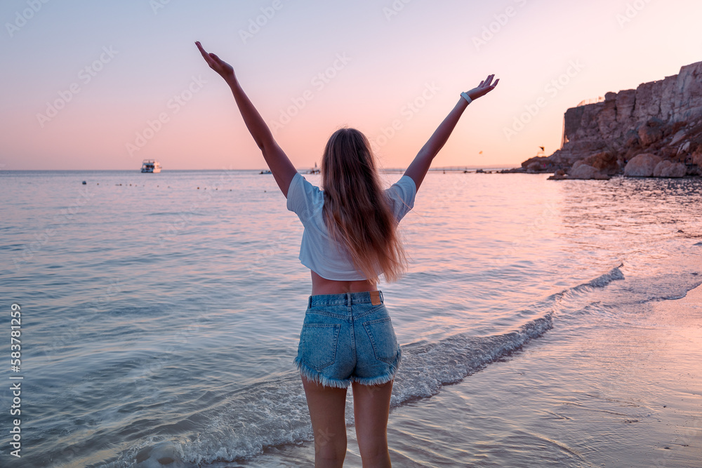 Pretty girl is enjoying sunset by sea. Blonde woman with long hair ...