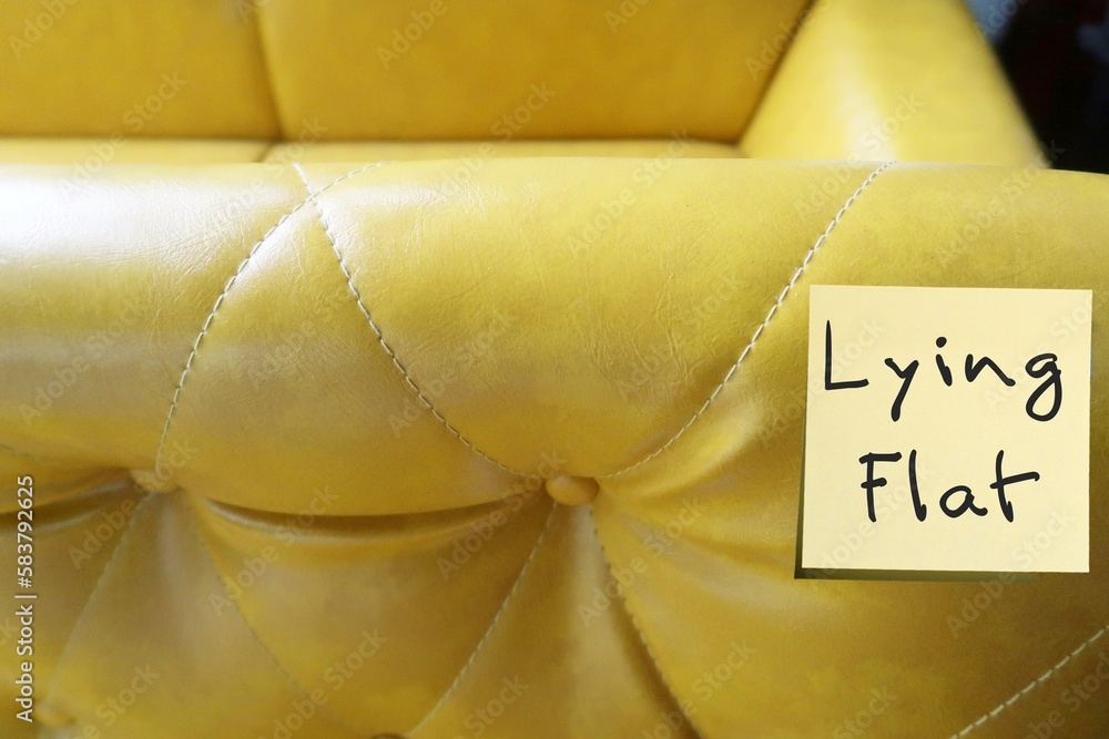 Yellow sofa with stick note written LYING FLAT, means movement of young people in China taking a ...
