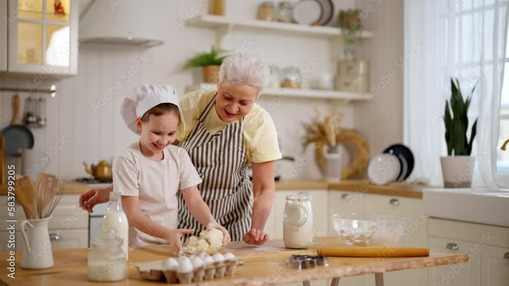 Granny teaching her granddaughter to cook cookies in kitchen at home ...