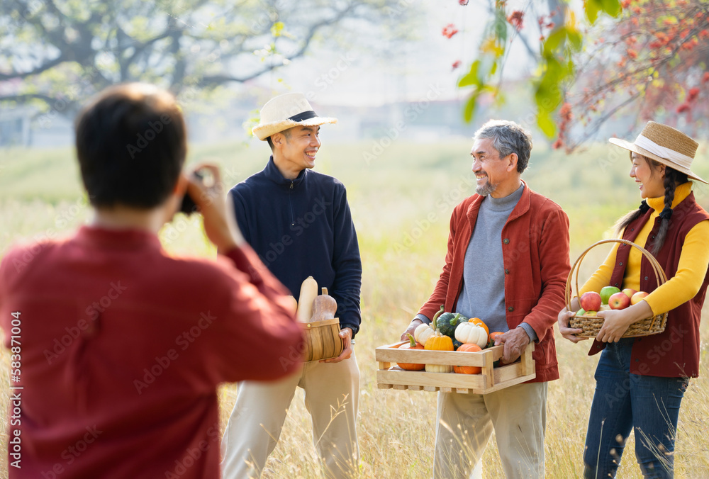 group of people holding bucket of fruit,smiling,taking photo while ...