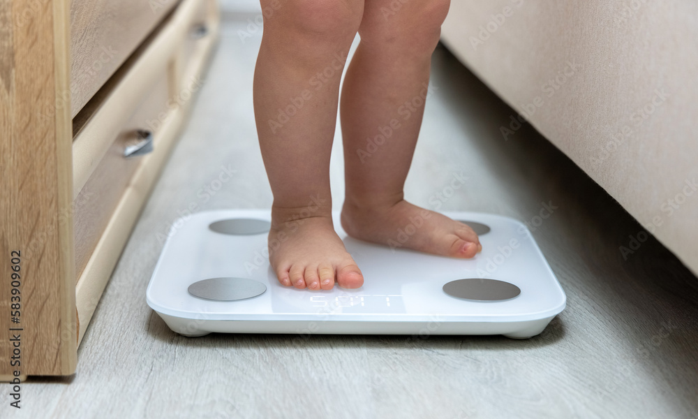 baby legs barefoot feet on body composition scale measuring weight home ...