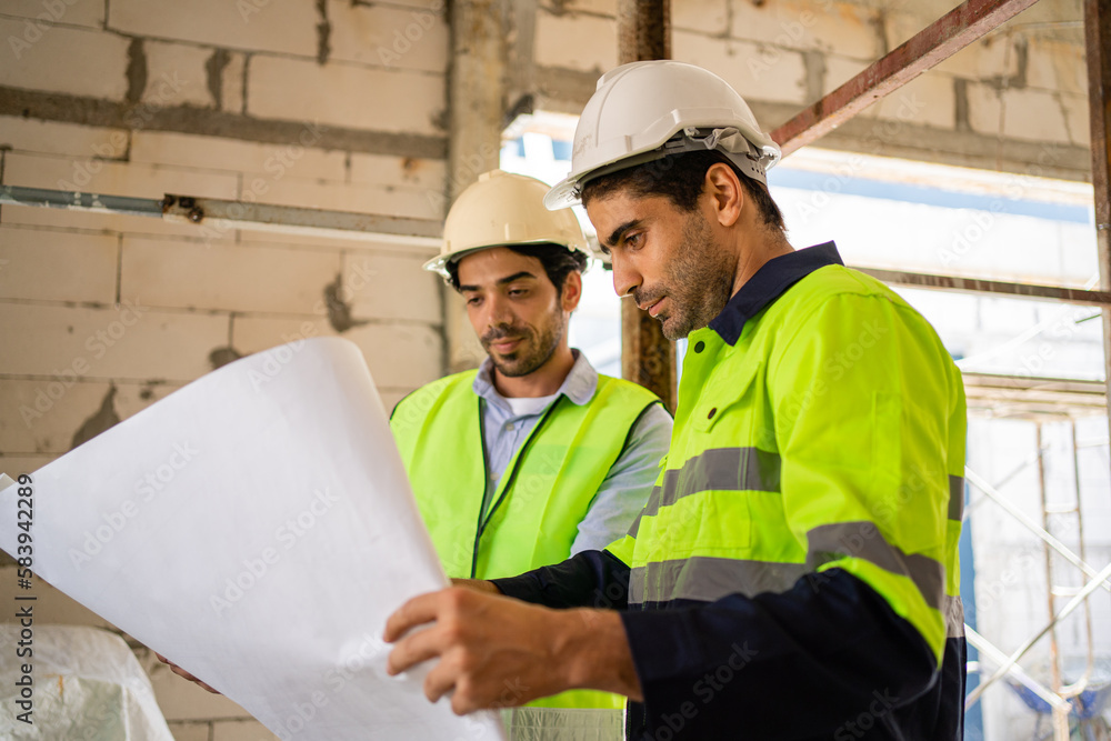 Structural Engineers and Architects Wearing hard hat and green jacket working at construction ...