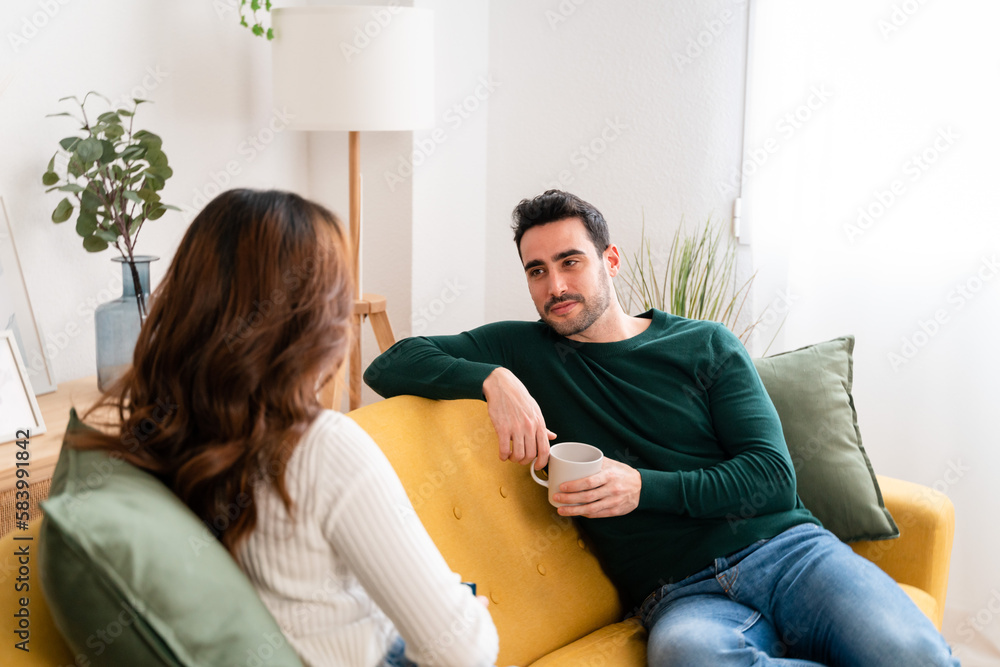 Young couple sitting on sofa and talking to each other Stock Photo ...