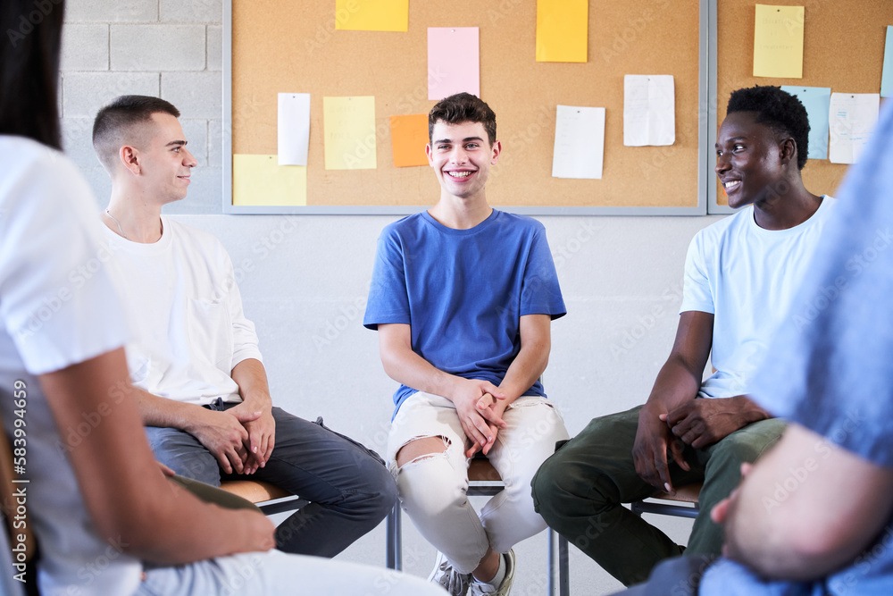 Group of high school students sitting on chairs in a circle and ...