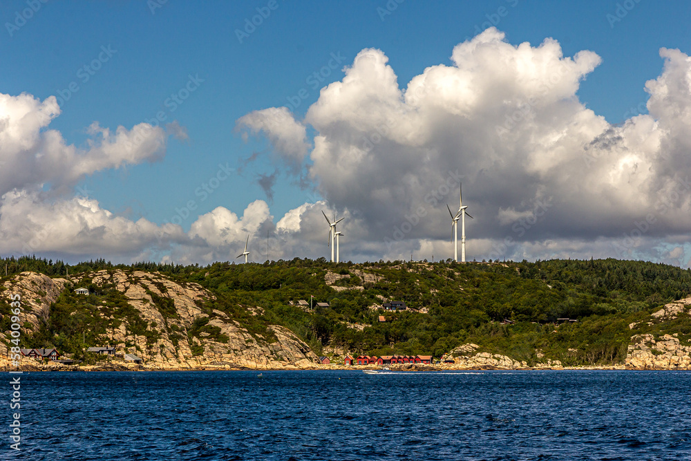 Wind turbines in Norway. Fluffy cumulus clouds in a blue sky Green ...