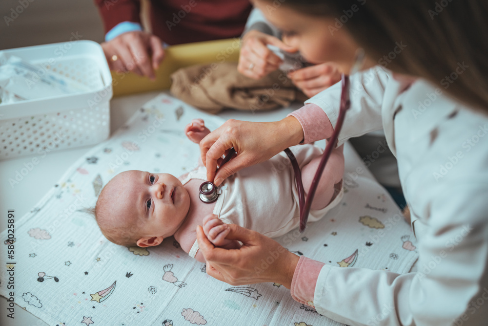 Pediatrician examining cute baby in clinic. Baby lying on her back and ...