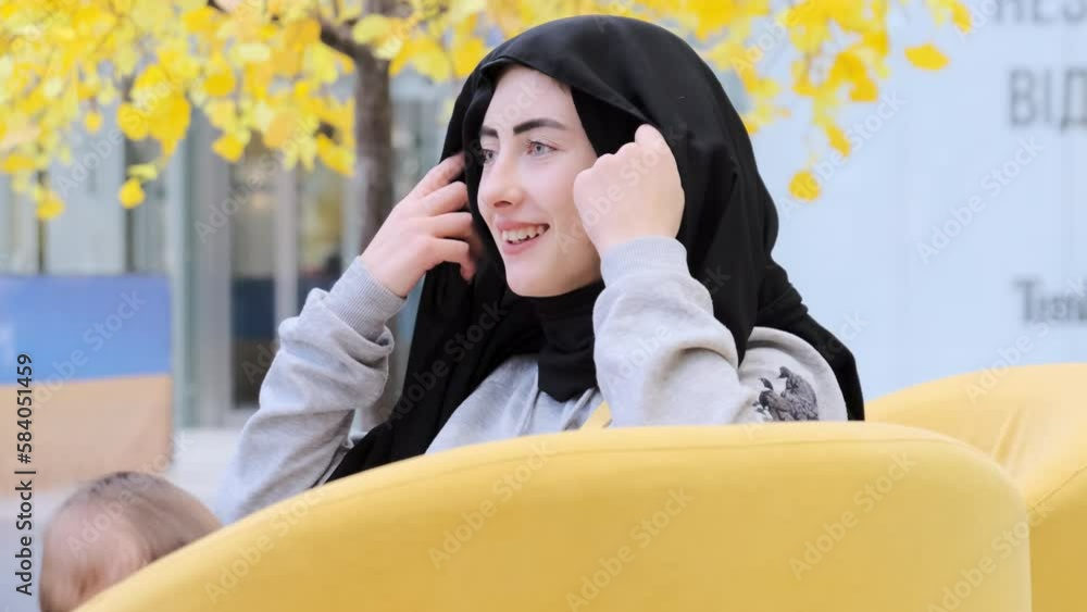 Muslim woman fixes black hijab on head and enjoys spending time with ...