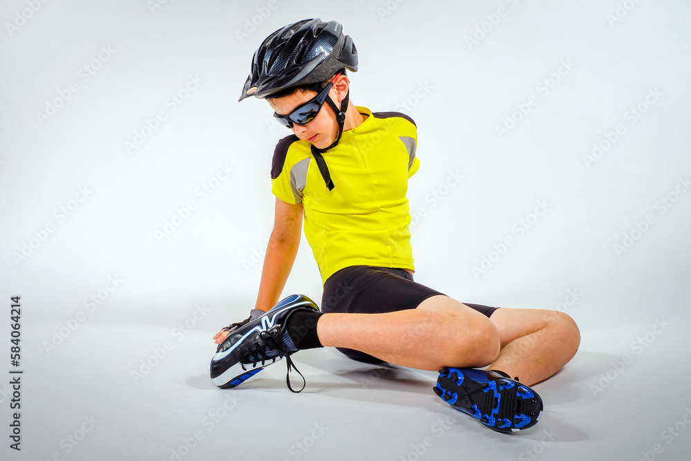 Young preteen boy model cyclist sitting on studio floor in biking ...