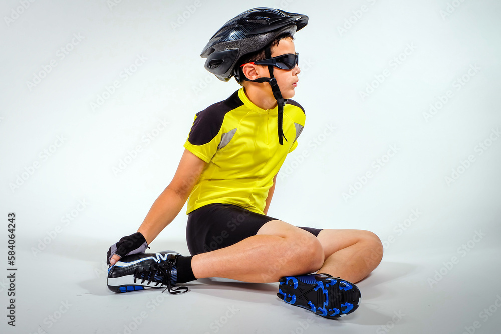 Young preteen boy model cyclist sitting on studio floor in biking ...