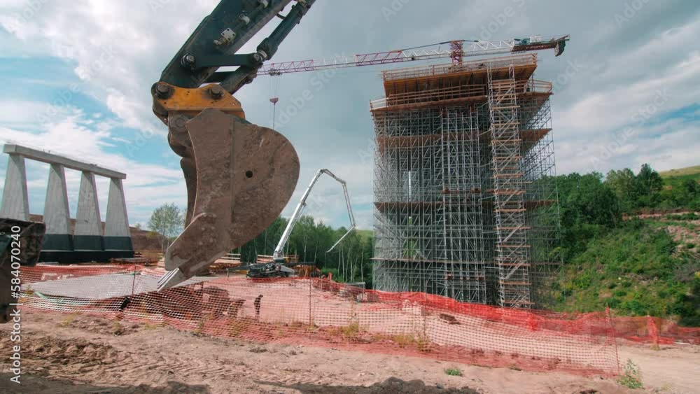 Large excavator bucket against road bridge support in scaffolds at ...