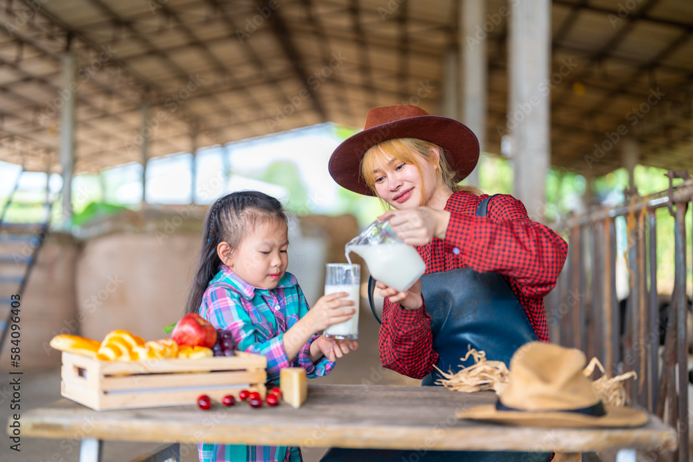 young woman dairy farm sitting with children in cowhouse on hay bale ...