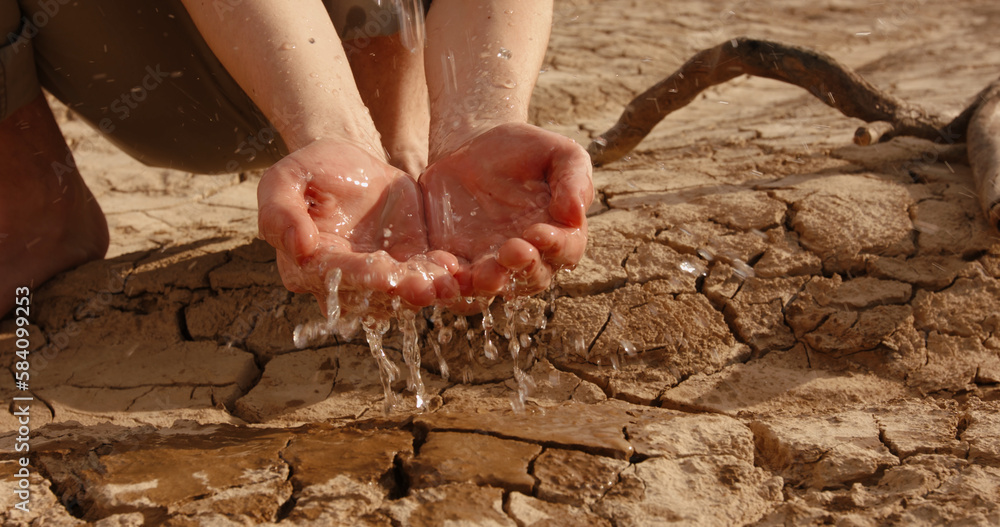 Water drops falling in hands of thirsty person catching water in desert ...