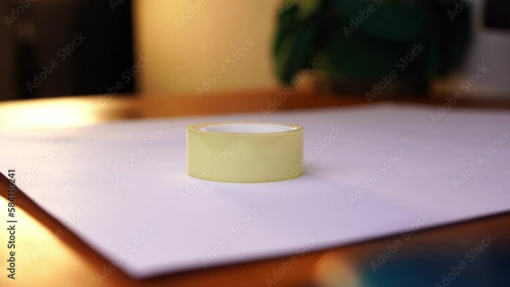Adhesive tape is put on a table with white paper and taken away again ...