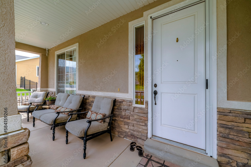 Entrance to a house with relaxing cushioned chairs at the open porch. A ...