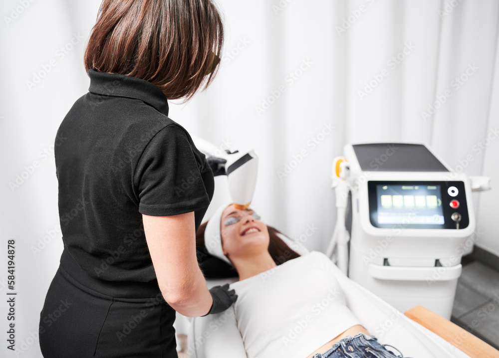 Cosmetologist using diode laser device while performing rejuvenation ...
