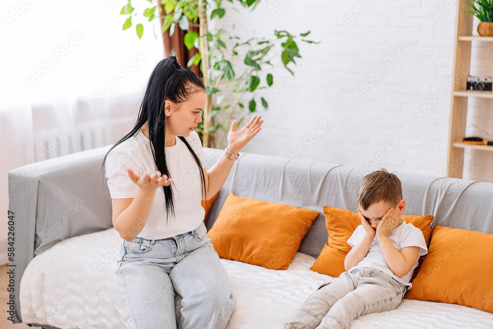 a serious young mother scolds her son for bad behavior, a working ...