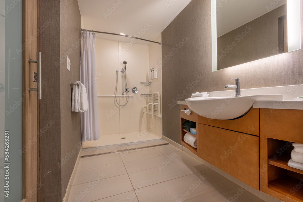 Wheelchair accessible hotel bathroom shower with tile floor and walls ...