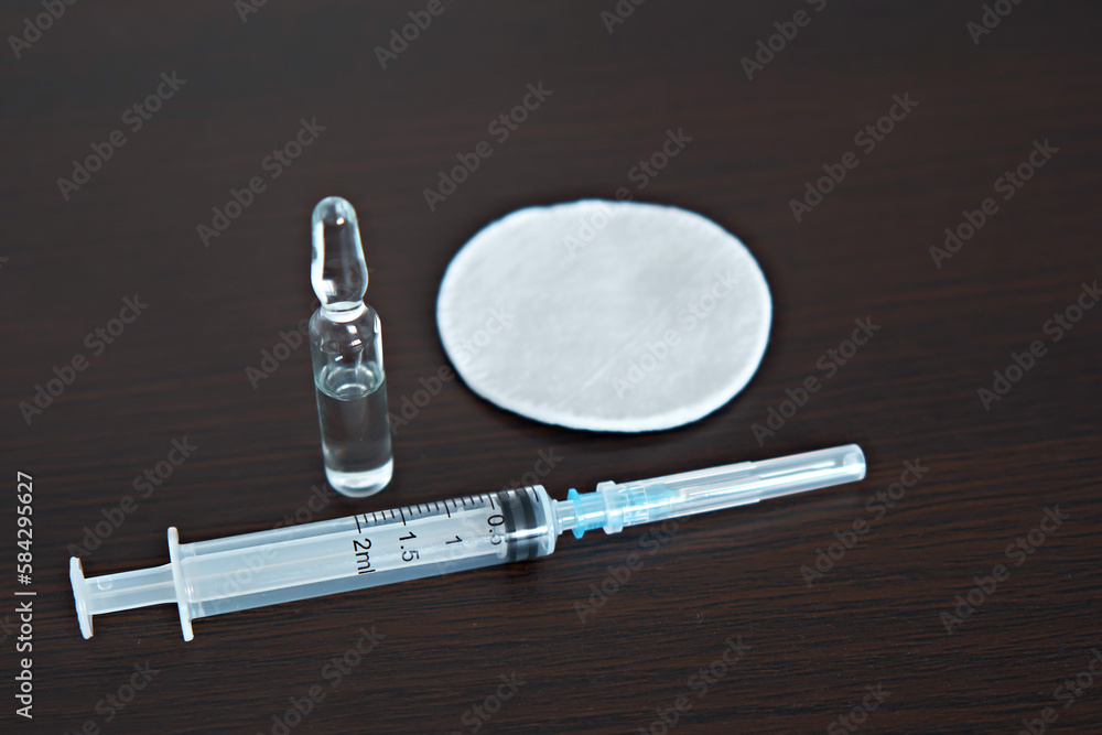 An ampoule with medicine and a syringe for injections on a dark ...