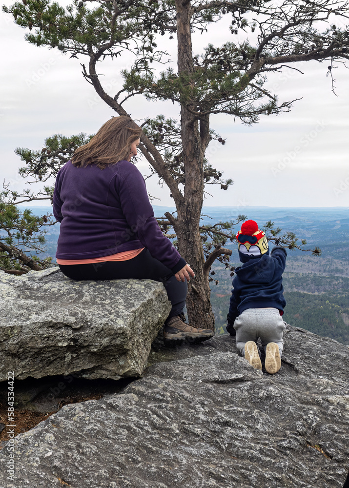 Mother and young son sitting of cliff edge after hiking up Cheaha State ...