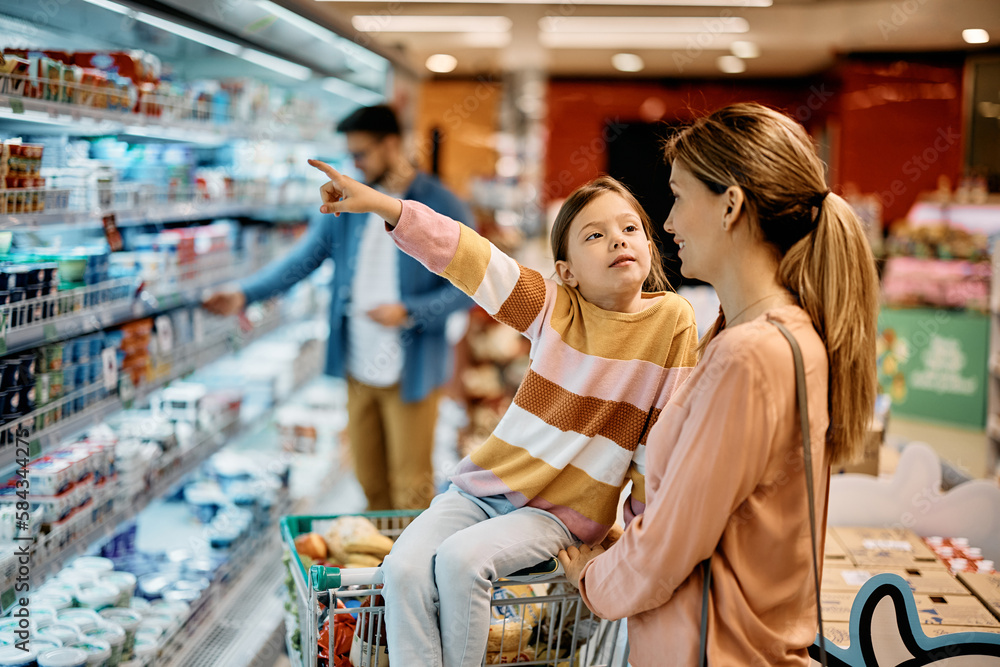 Little girl talks to her mother while shopping in supermarket and ...