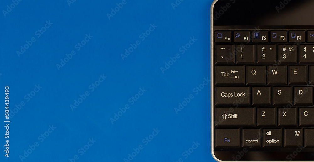 Half of a computer keyboard on a blue isolated background. Black ...