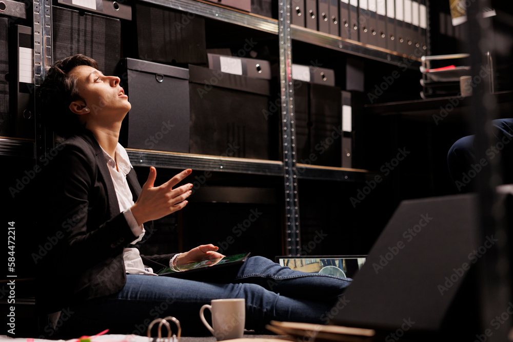 Tired private detective working overtime in arhive room, looking at ...