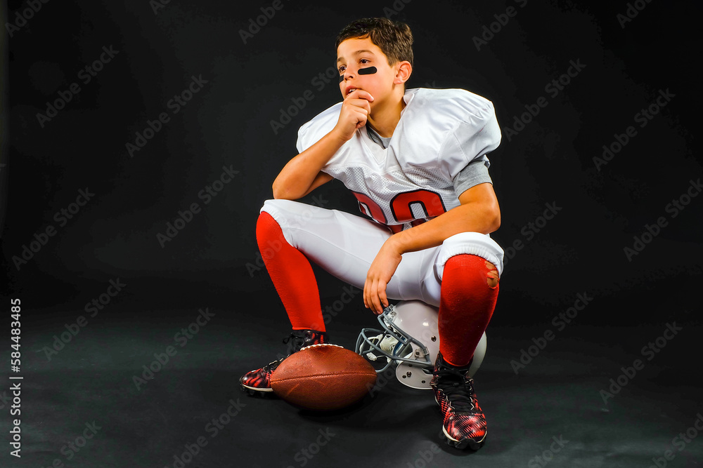 Foto de Youth preteen boy football player sitting on helmet in studio ...