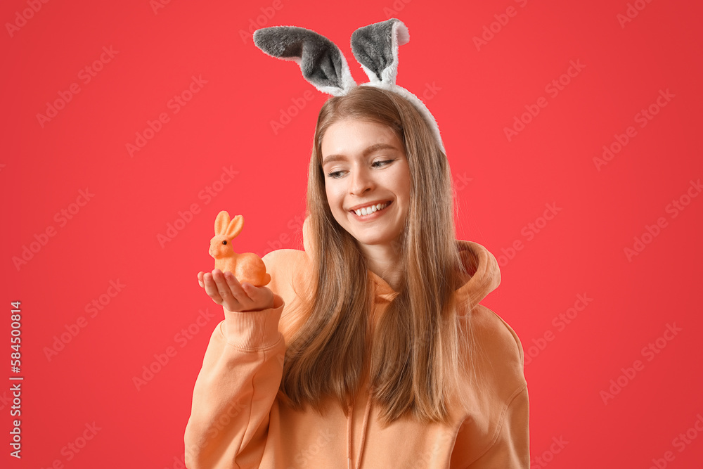 Young woman in bunny ears with Easter rabbit on red background Stock ...