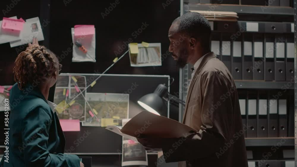 Detectives colleagues examining criminal files in office, looking at ...