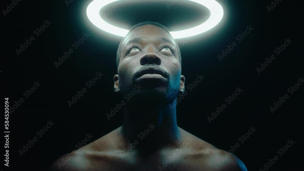 Young shirtless black man looking upwards at the ring light, posing ...