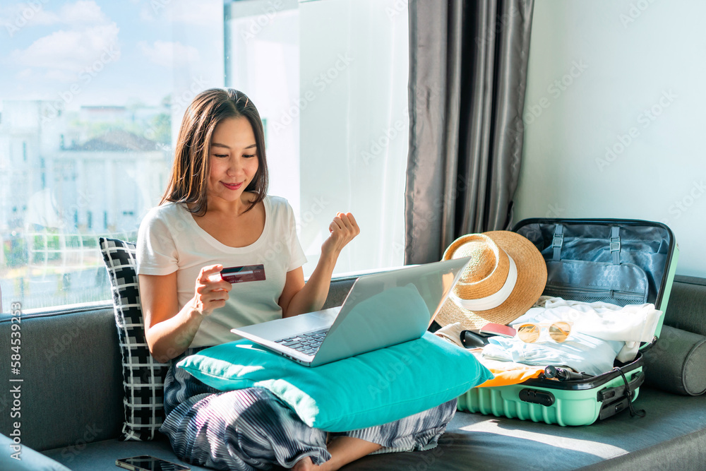 Foto de Happy young Asian woman using credit card booking flight ...