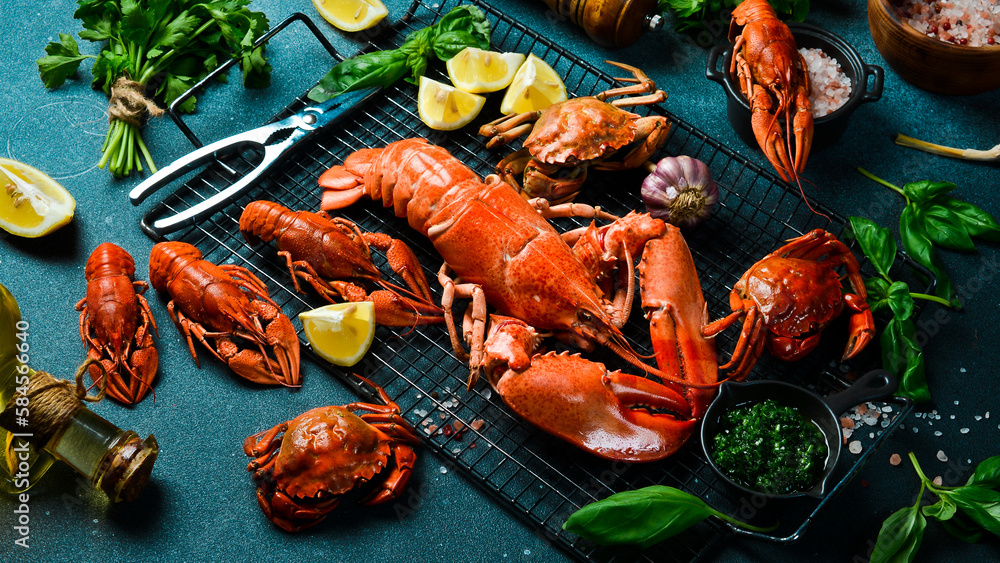 Boiled lobster, crab and crayfish with lemon and basil on a black slate ...