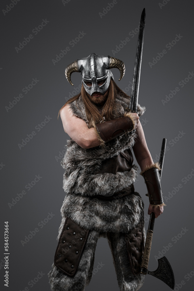 Shot of barbarian from north with fur and long hairs holding sword and ...