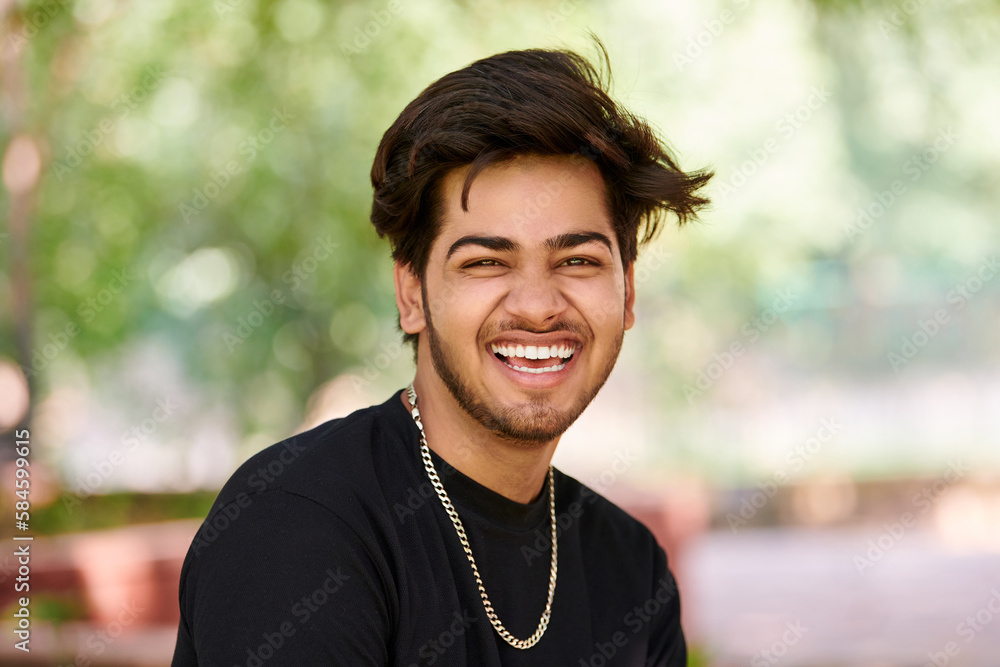 Smiling young indian man candid portrait in black t shirt and silver ...
