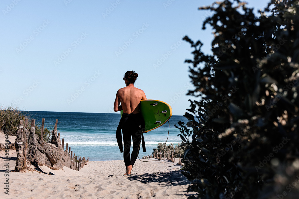 Surfer with wetsuit getting ready for a surf session. Boy walking on ...