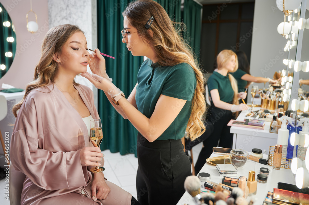Beauty specialist applying eyeshadow on client eyelid in visage studio ...