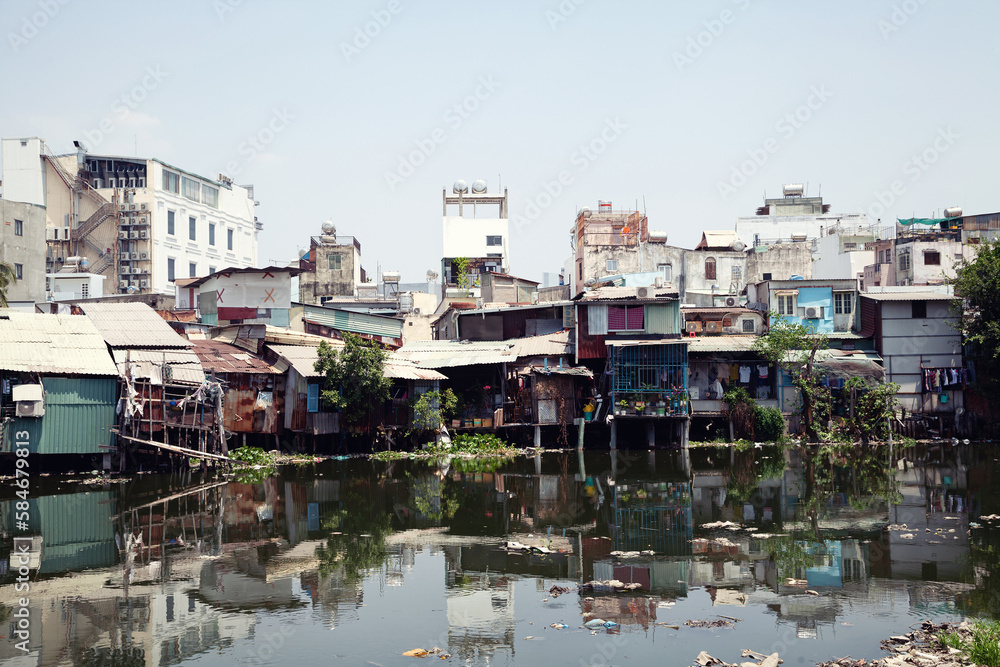 Old houses on stilts in the slums of Saigon along a river full of trash ...