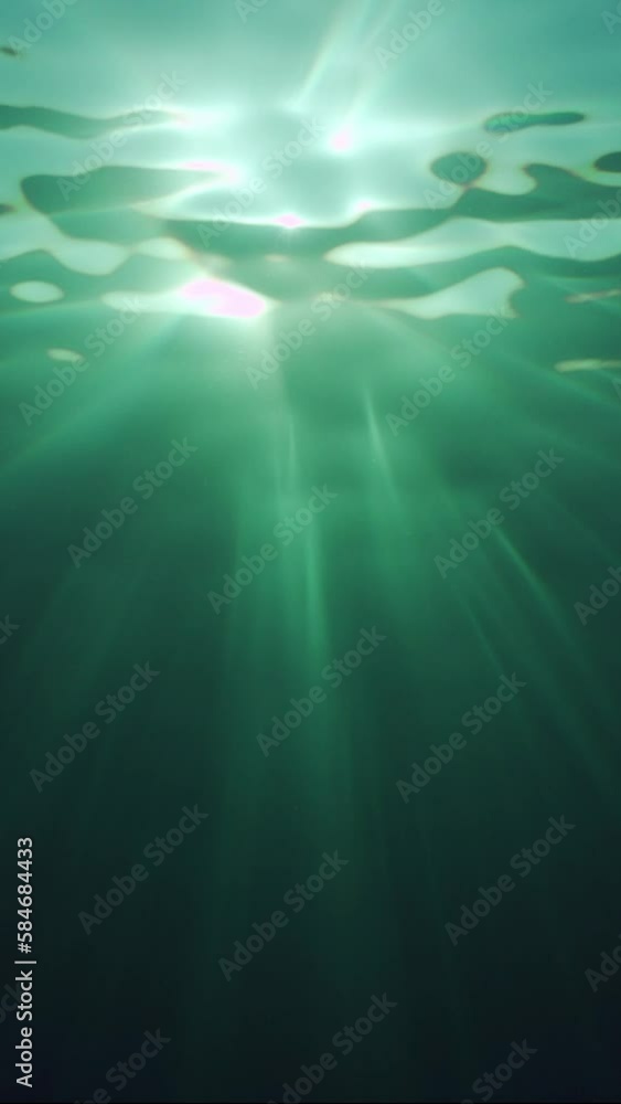 Sunlight at dawning penetrates through waves on water surface. Sun rays ...