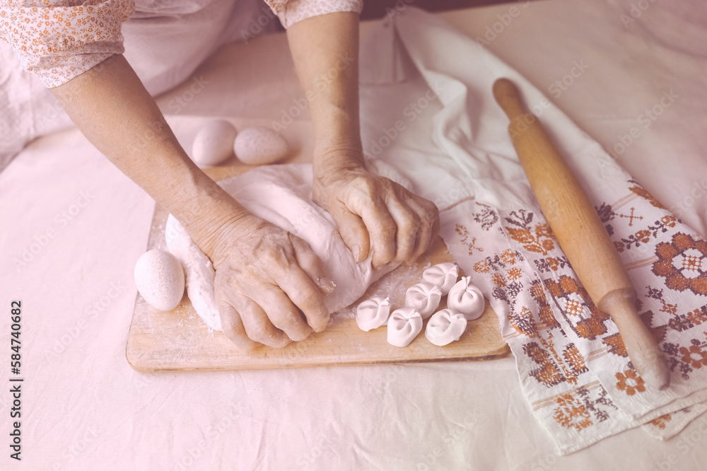 Elderly woman hands rolling out dough in flour with rolling pin in her ...