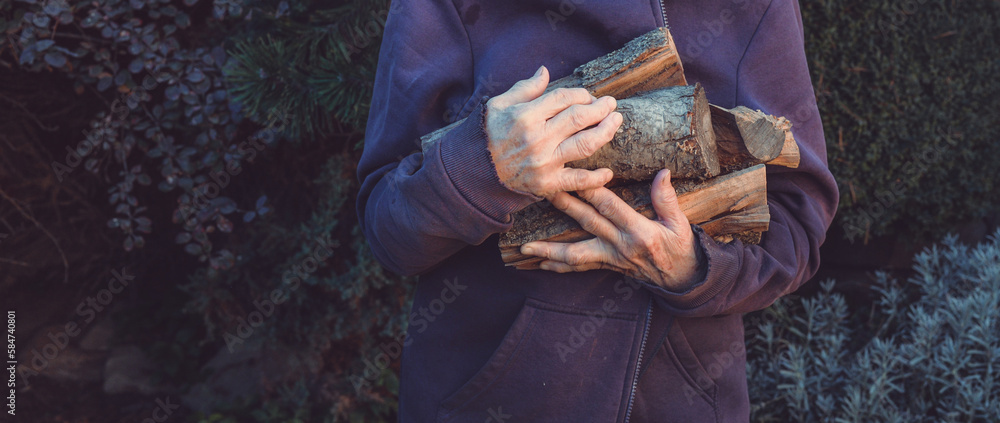 Old man in a tainted rattle holds firewood in overworked hands. Poor ...
