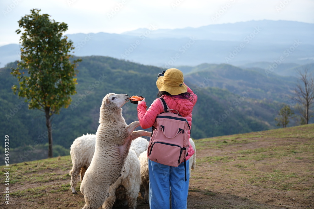 Female tourist wearing a bright orange down coat wearing yellow hat is ...