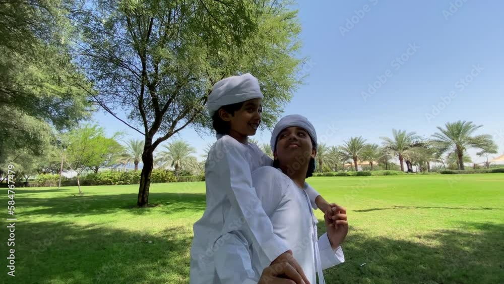 Emirati kids wearing traditional dress kandura playing together in a ...