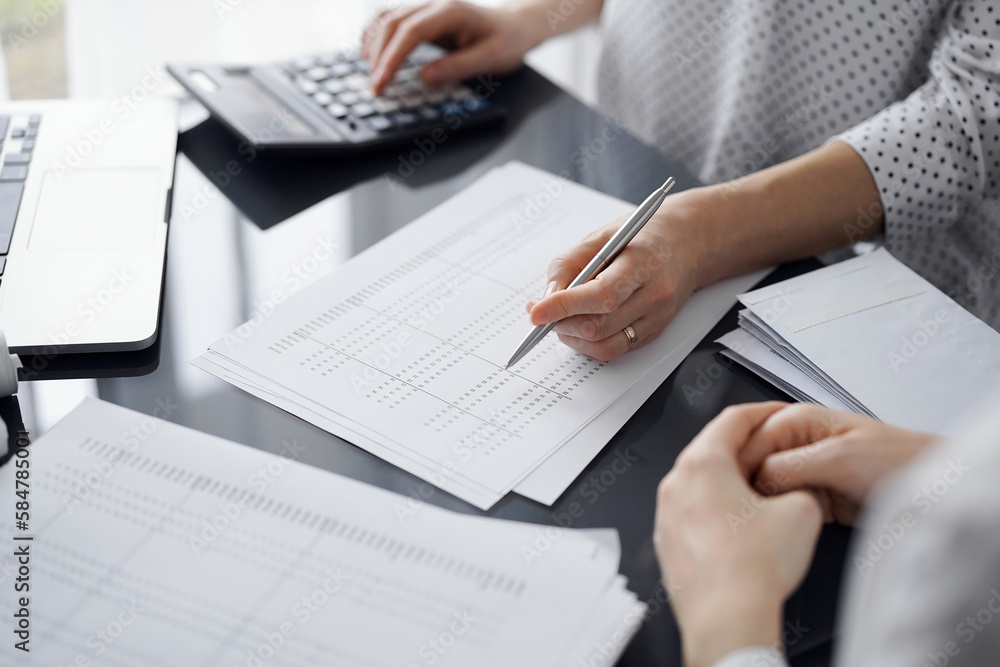 Woman accountant using a calculator and laptop computer while counting ...