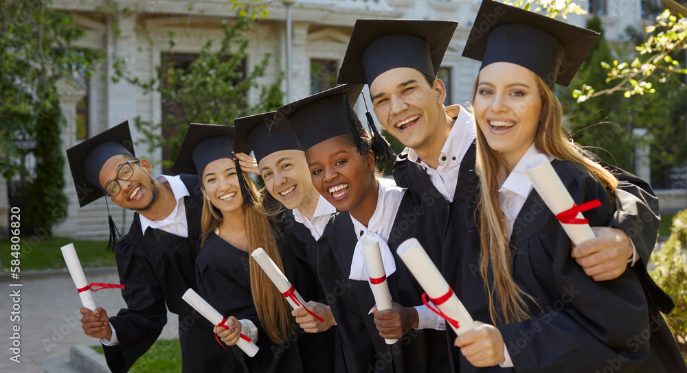 Happy team of students in graduation gowns and caps celebrating ...