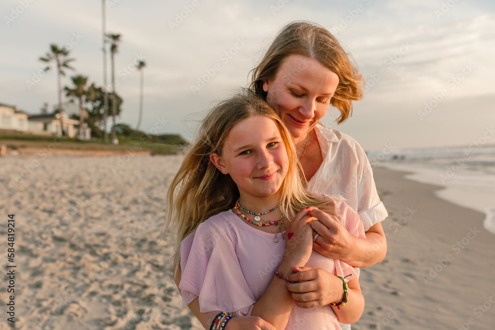 Smiling tween girl hugging her mother on the beach Stock Photo | Adobe ...
