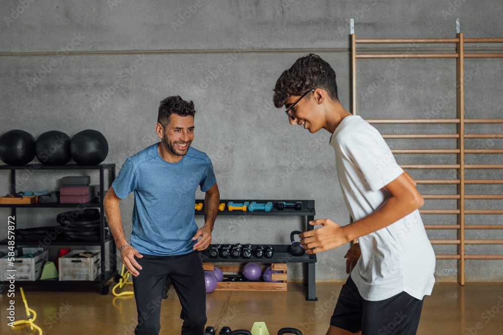 Smiling personal trainer encouraging boy during circuit training ...